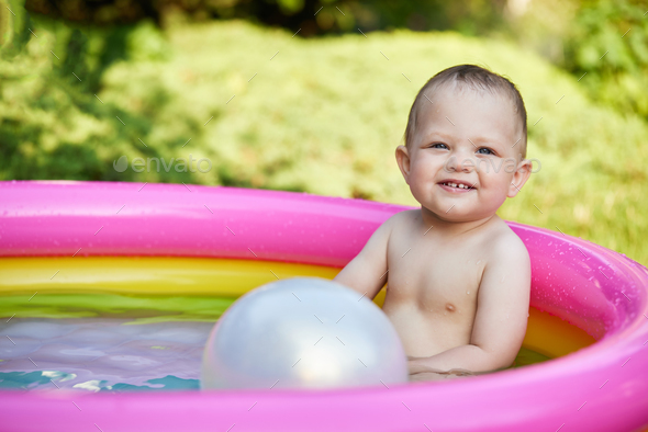 cute baby girl swimming in kid inflatable pool Stock Photo by producer555