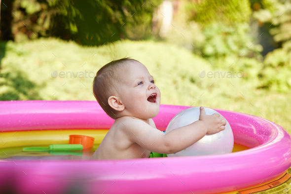 cute baby girl swimming in kid inflatable pool Stock Photo by producer555