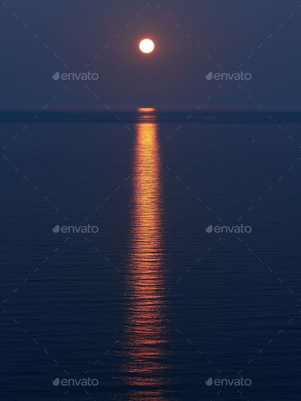 Full moon reflecting in the calm sea at night time Stock Photo by wirestock