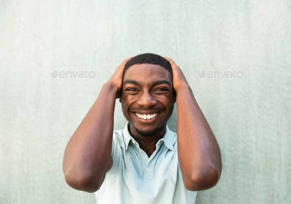 Close up laughing young African American man with hands behind head ...