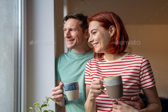Smiling happy couple drinking coffee looking out window Stock Photo by ...