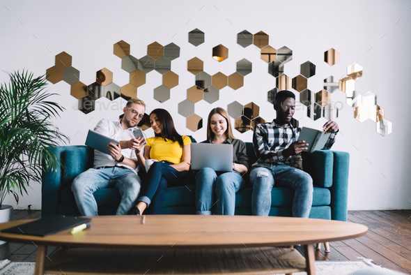 Multiethnic people chilling together on couch Stock Photo by GaudiLab