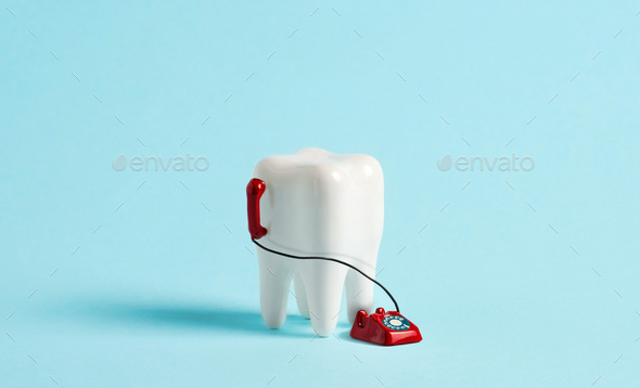 Model of human tooth with miniature phone on blue background. Stock ...