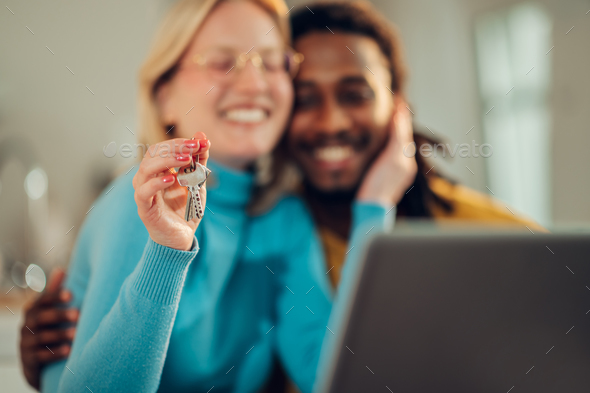 Close-up of hand holding the new home keys while a happy multiracial ...