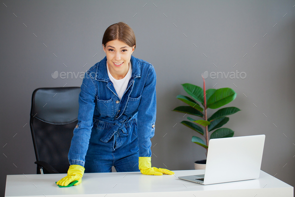 Portrait of happy female worker cleaning computer desk Stock Photo by ...