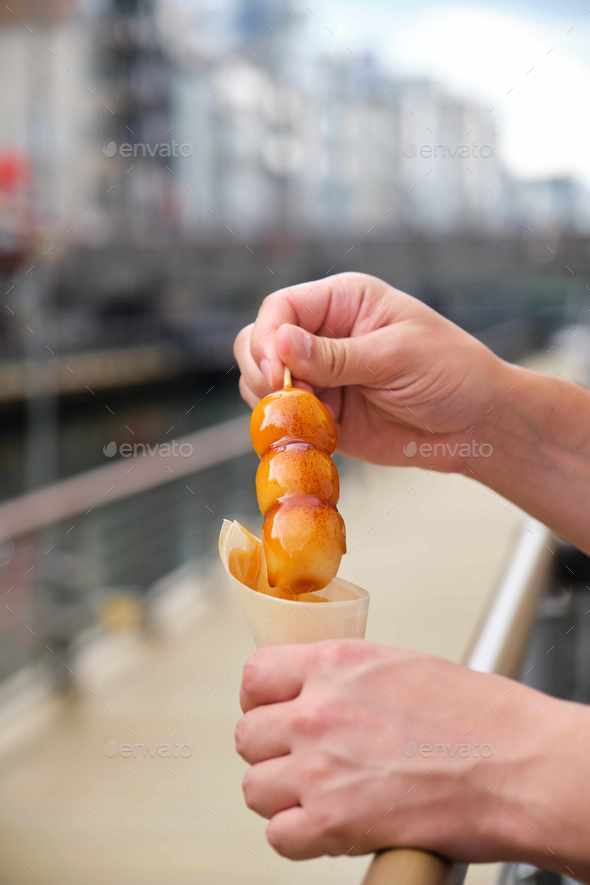Unrecognizable person eating mitarashi dango at street. Stock Photo by ...