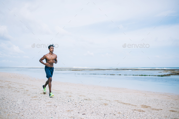 Sweaty ethnic muscular man making recreational run on seashore Stock ...