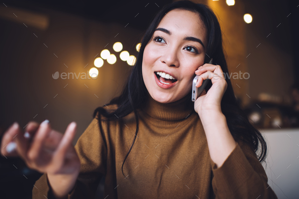 Charming female with brunette hair gesturing while phoning via ...
