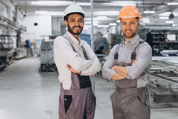 Two international male workers in overalls on the background of the ...