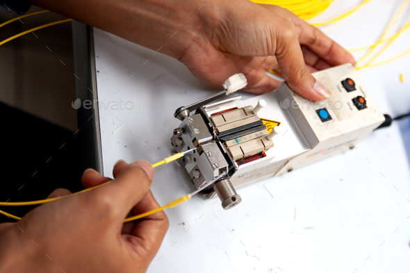 Technician cleaving an optical fiber, a crucial process for a good ...
