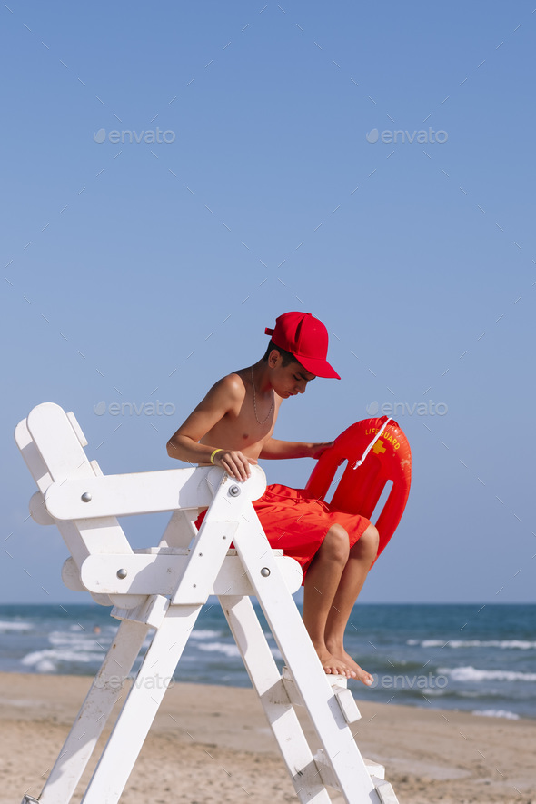 Boy lifeguard next to the watchtower on the beach Stock Photo by ...