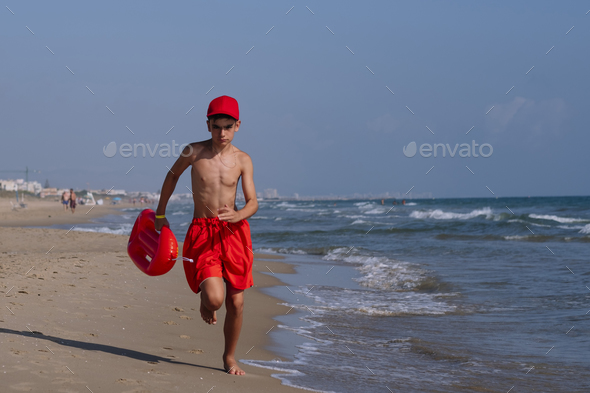 Lifeguard boy with lifeguard float running on the beach Stock Photo by ...