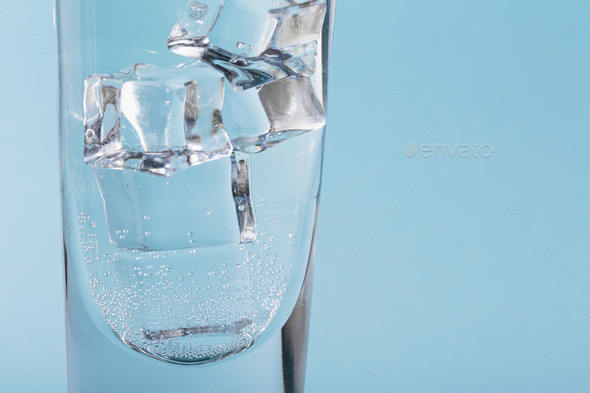 Glass of pure cold sparkling water with ice cubes on blue background Stock Photo by svittlana