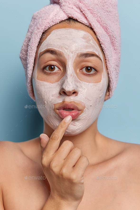 Vertical shot of serious charming woman keeps finger on lips poses ...