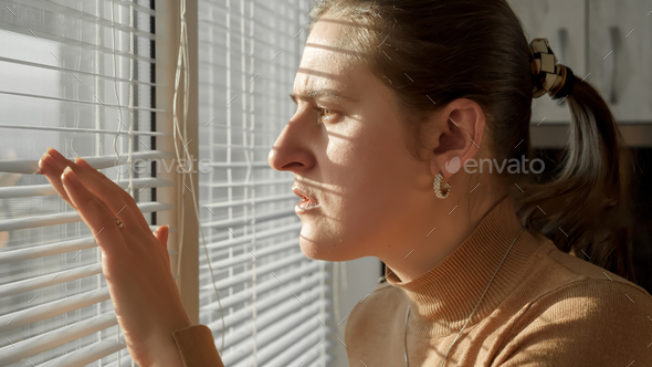 Shocked scared woman looking outdoors through window. Crime witness ...