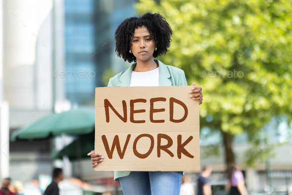Unemployed black woman standing on street, holding Need Work placard ...