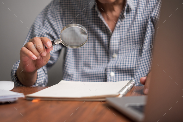 Asian senior businessman holding magnifying glass check work documents ...