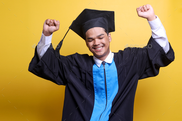 Young happy man wearing graduation cap and ceremony robe enjoy dancing ...
