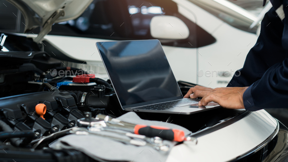 Car mechanic using laptop computer examining tuning fixing repairing ...