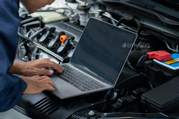 Car mechanic using laptop computer examining tuning fixing repairing ...