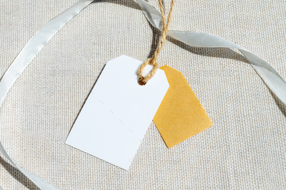 Two rectangular tags with a rope on a gray fabric. empty label mockup ...