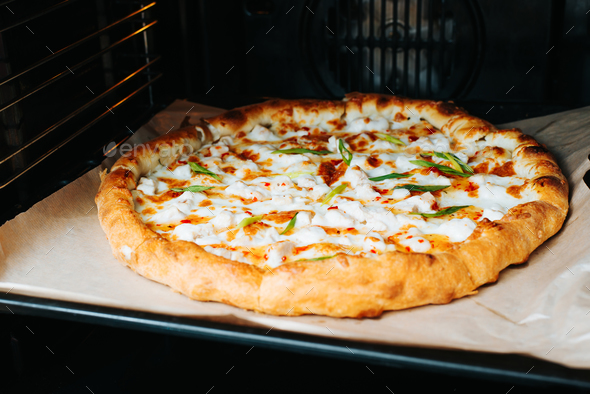 Freshly cooked pizza in an open oven in home kitchen. Close-up ...
