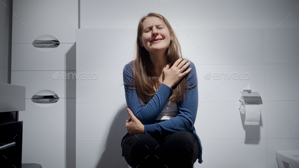 Portrait of woman suffering from depression crying on toilet at home ...