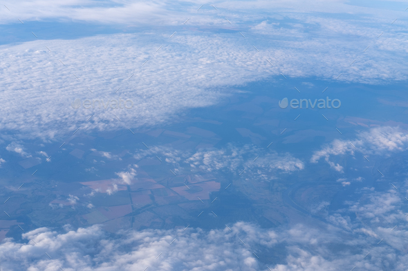 The view from the plane window to the clouds and the ground. The ...