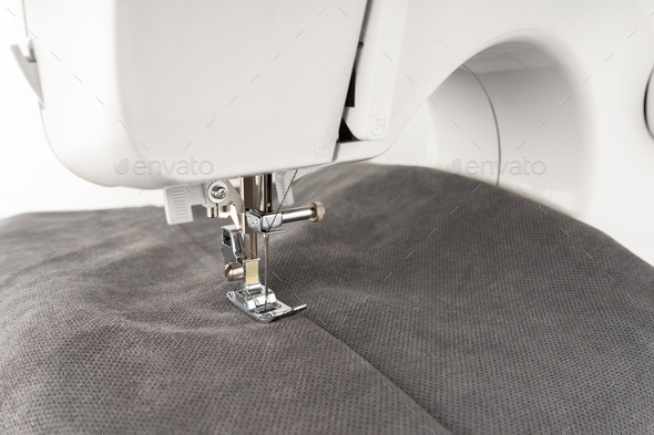 Modern sewing machine with gray fabric Stock Photo by Kateryna_Maksymenko