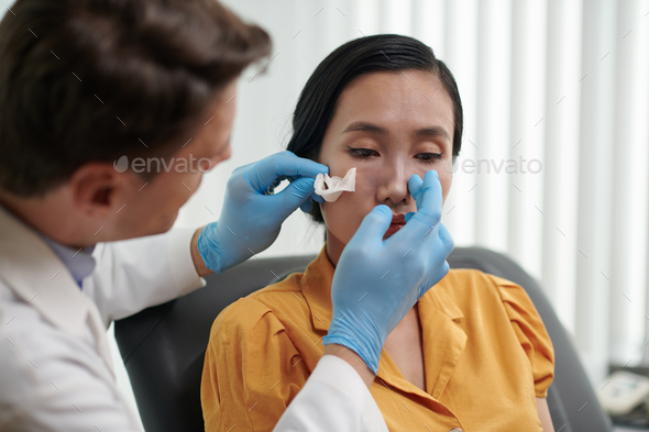 Surgeon Examining Nose of Patient Stock Photo by DragonImages | PhotoDune