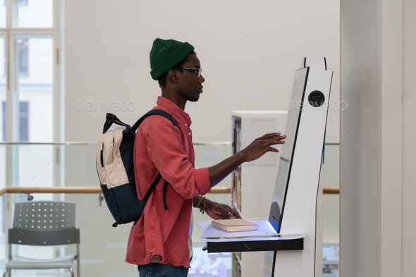 Concentrated African American man student stands near terminal to check ...