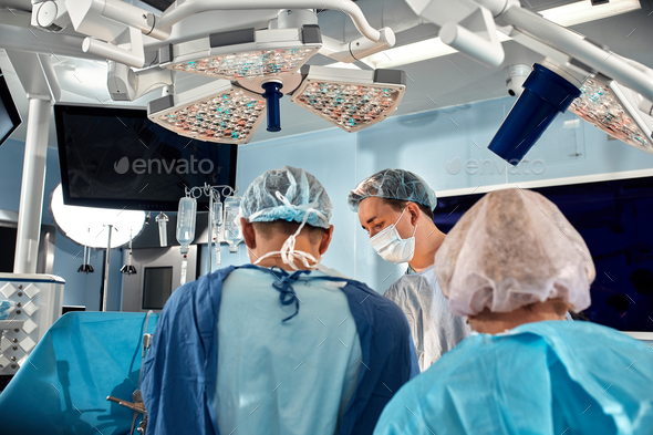 Surgeons team during complex surgical operation in a bright sterile ...