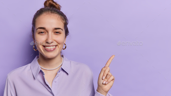 Confident young woman showcases logo on empty space her smile inviting ...