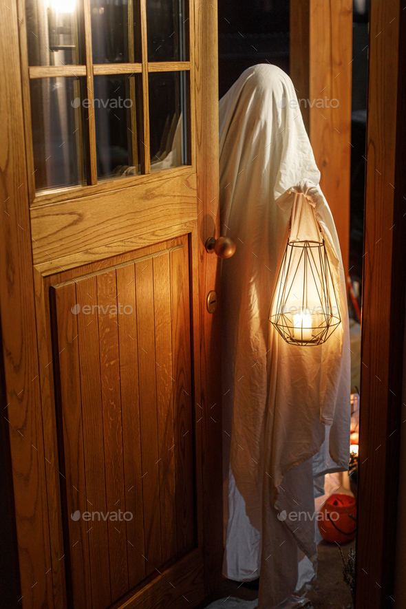 Scary ghost with glowing lantern at doors in spooky atmospheric night ...