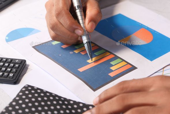 man hand with pen analyzing bar chart on paper Stock Photo by towfiqu98