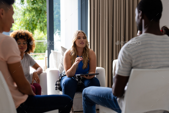 Happy diverse group of friends using tablet and talking in group ...