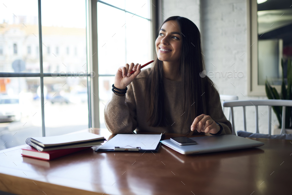 Positive female student with A4 paperwork for learning looking away and ...