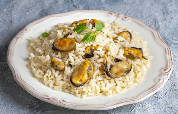 Mussel rice pilaf. Rice with mussels on small white plate on ceramic ...