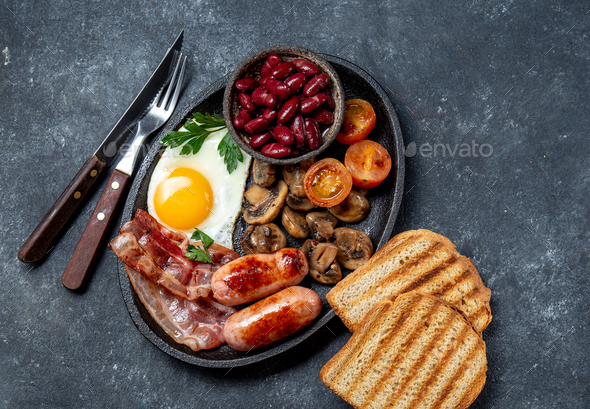Full fry up English breakfast with fried eggs, sausages, bacon, black ...