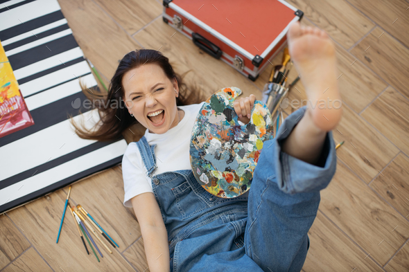 Female artist with palette falling down with smile in studio Stock ...