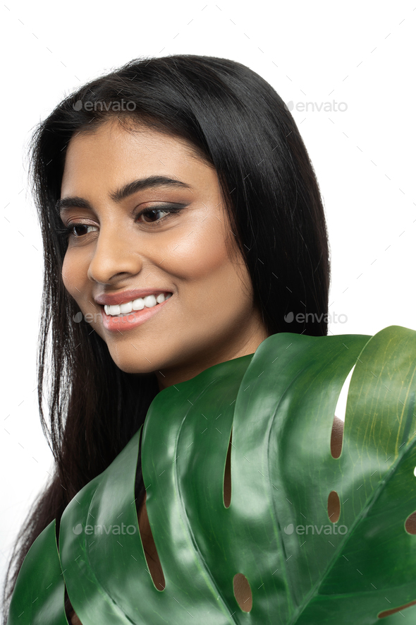 Beautiful Indian woman with a smooth skin holding green tropical leaf ...