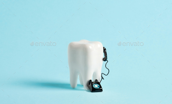 Model of human tooth with miniature phone on blue background. Stock ...