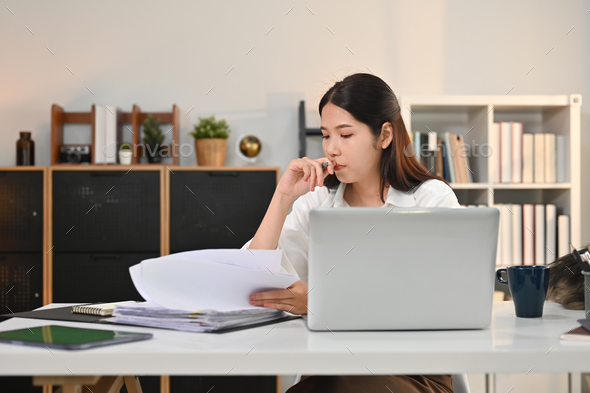 Concentrated female siting in front of laptop computer at working desk ...