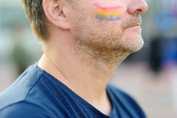 Close up view of face man activist with painting rainbow on cheek ...