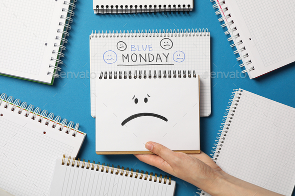 Notepad with text Blue Monday and notepad with sad emoji in hand on ...