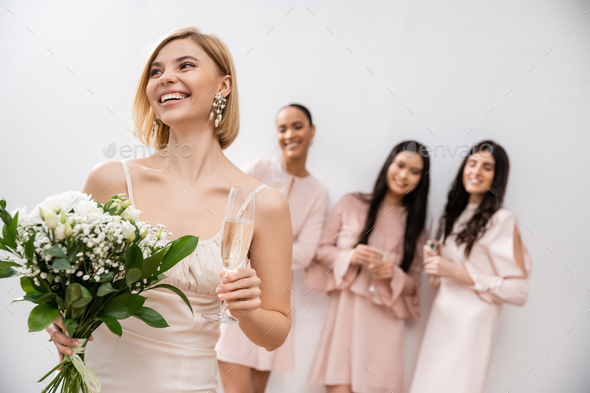 cheerful bride in wedding dress holding bridal bouquet and champagne ...