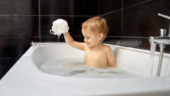 Happy smiling baby boy having fun and washing in the bath. Importance ...