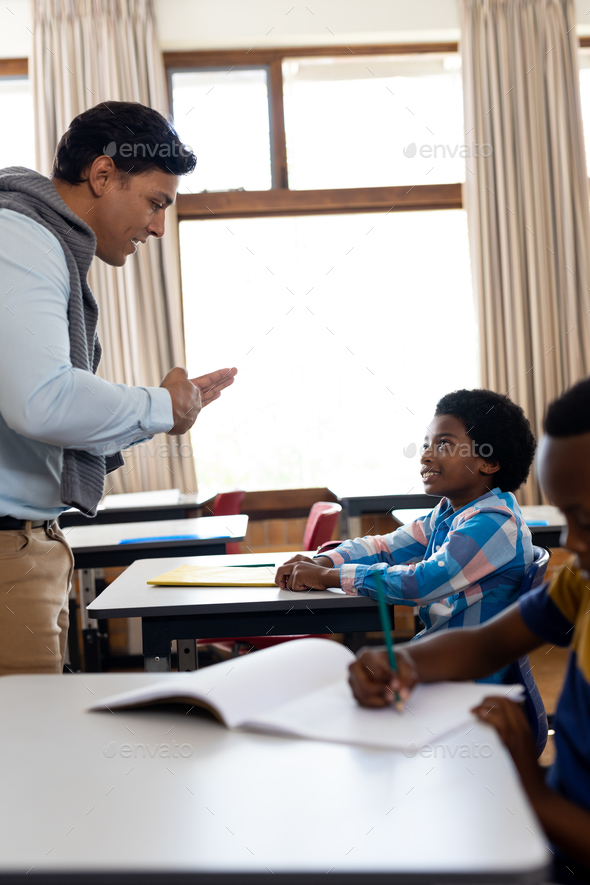 Diverse male teacher teaching school boy using sign language in class ...