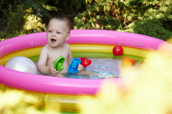 cute baby girl swimming in kid inflatable pool Stock Photo by producer555