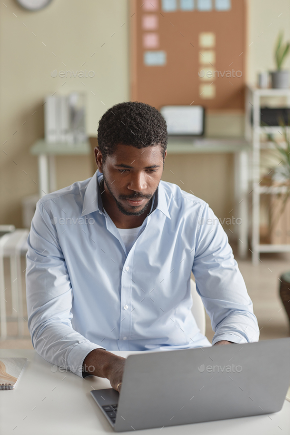 Handsome black man as businessman using computer at desk in office ...